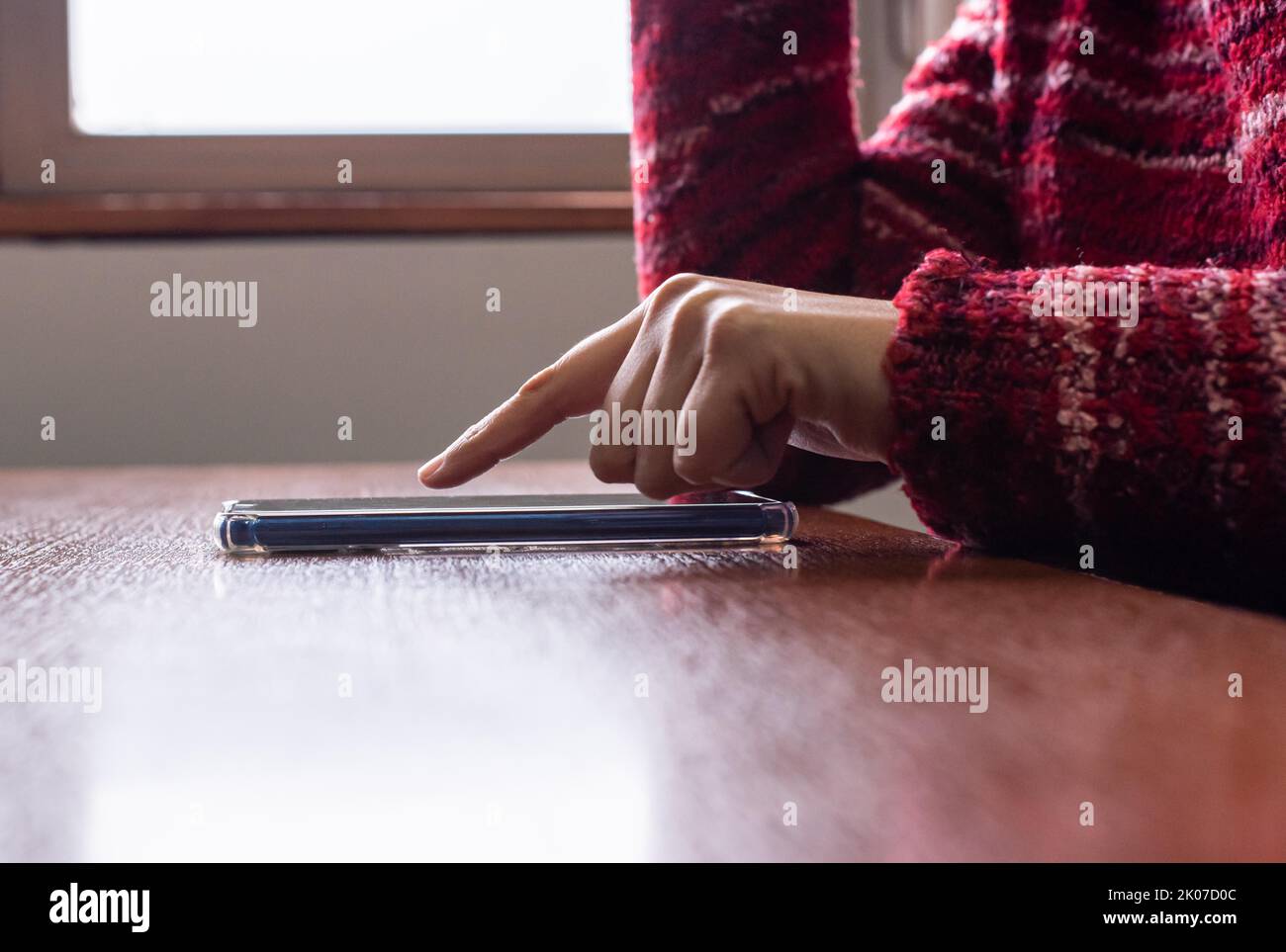 Side view of female hand using her smartphone touch screen near the ...