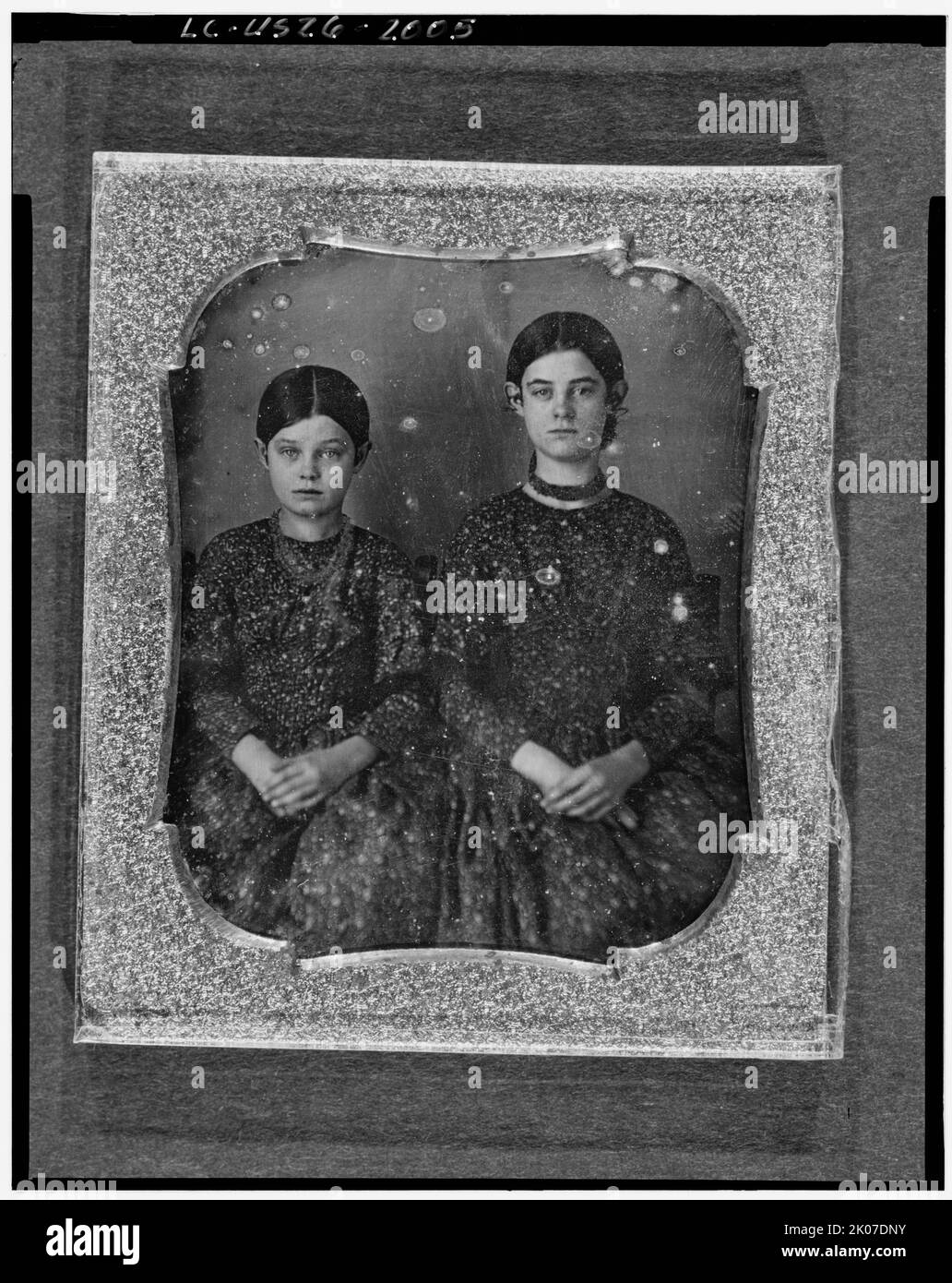 Group portrait of two unidentified girls, three-quarter length, seated, facing front, between ...