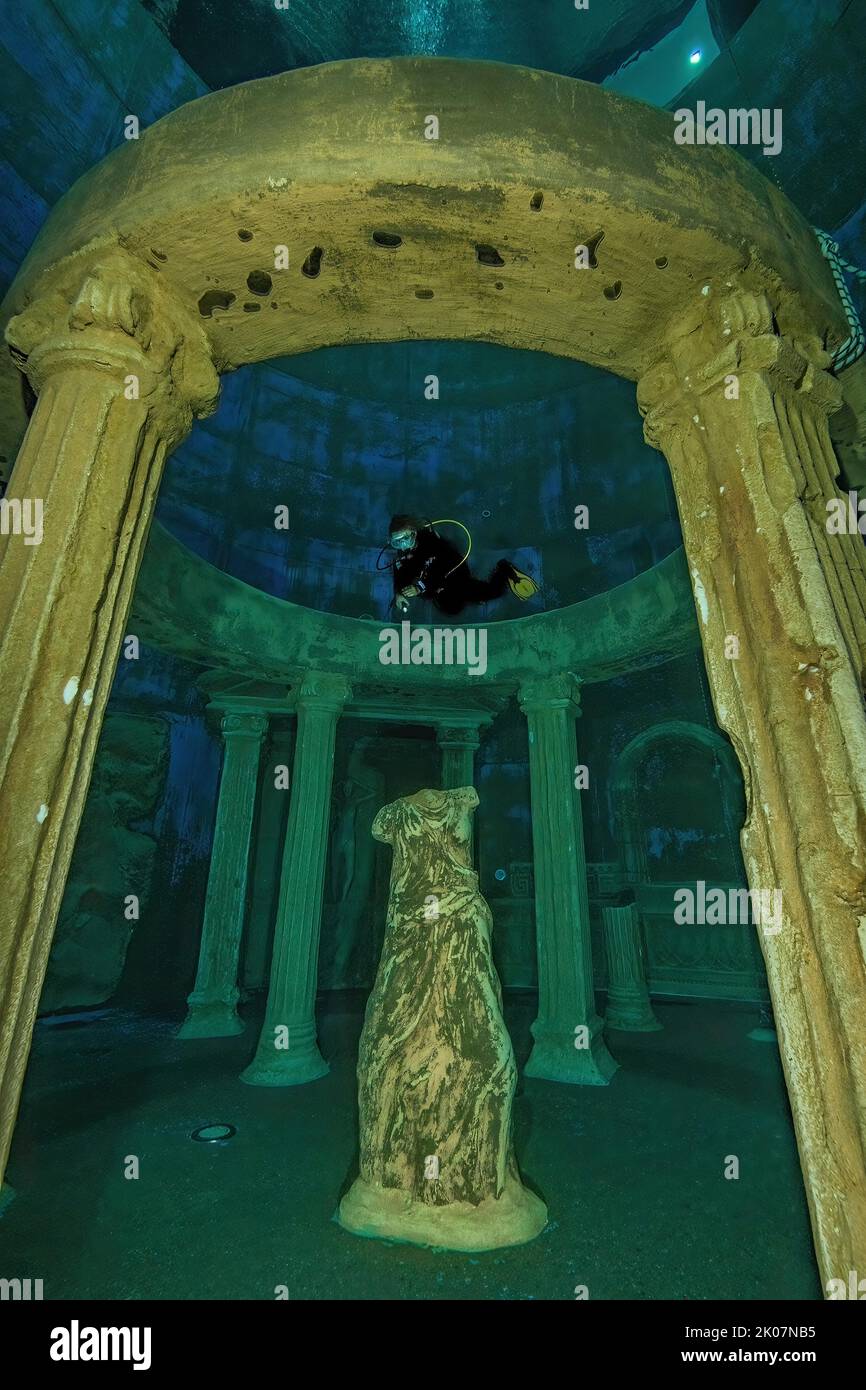 Diver dives over stylised ruins of antique temple at a depth of 20 ...