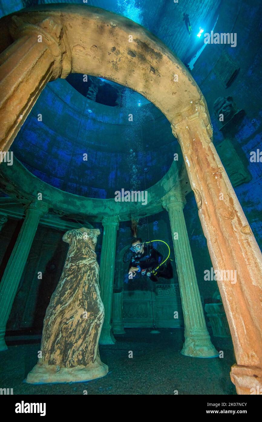 Diver dives through stylised ruin of antique temple round temple in 20 ...