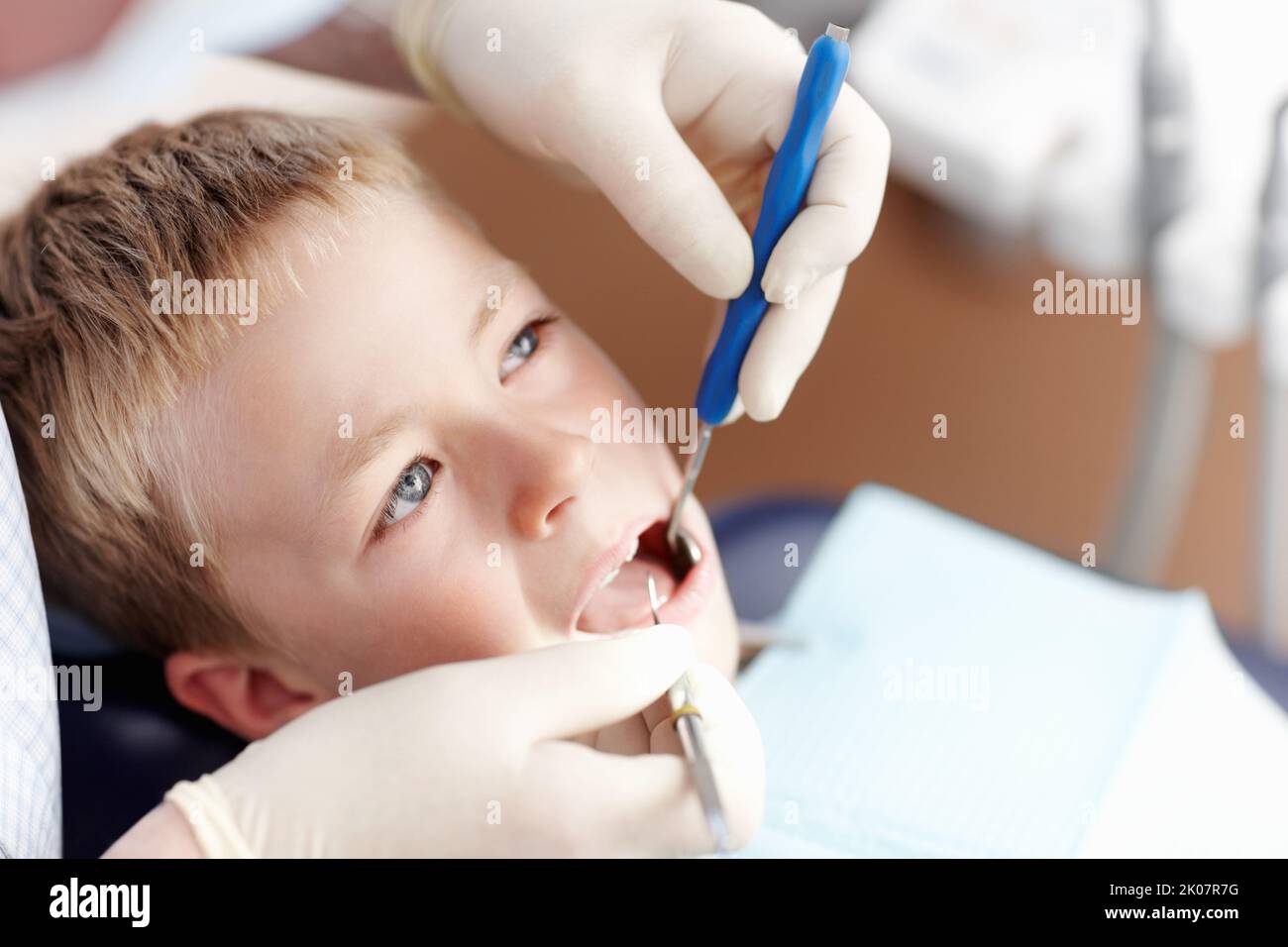 Boy taking dental checkup. High angle view of dentist checking up boys ...