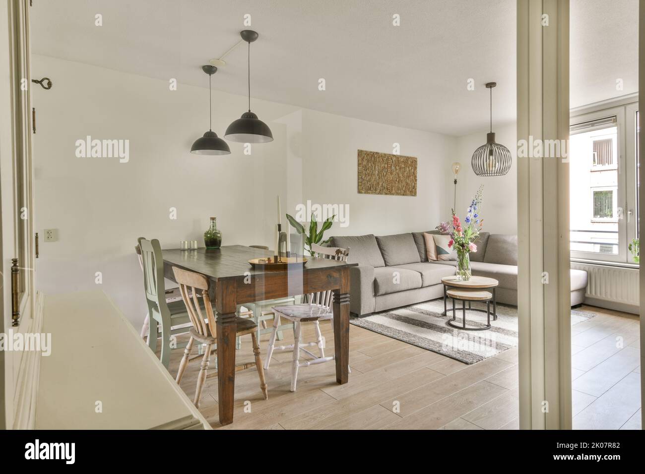 Shabby wooden table with chairs and vase located near comfortable couch ...