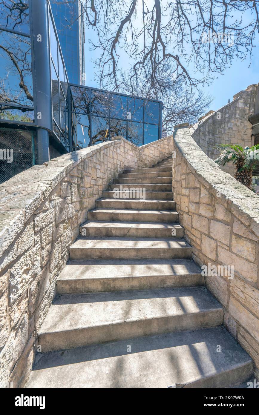 Outdoor staircase with sunlit concrete steps and stone railings on a ...