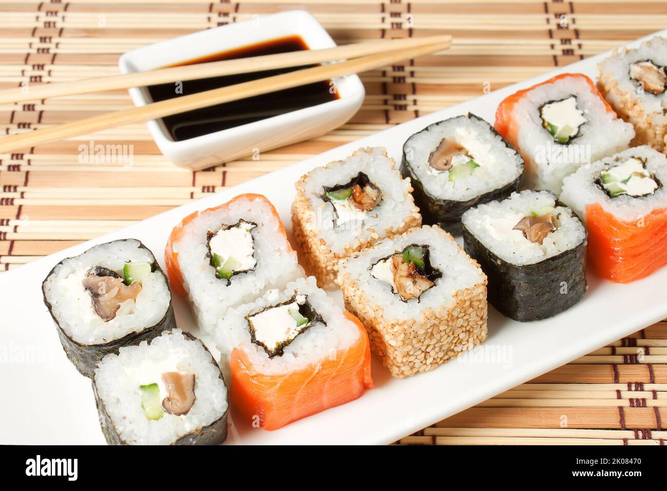 sushi assortment on white plate, with soy sauce over bamboo background ...