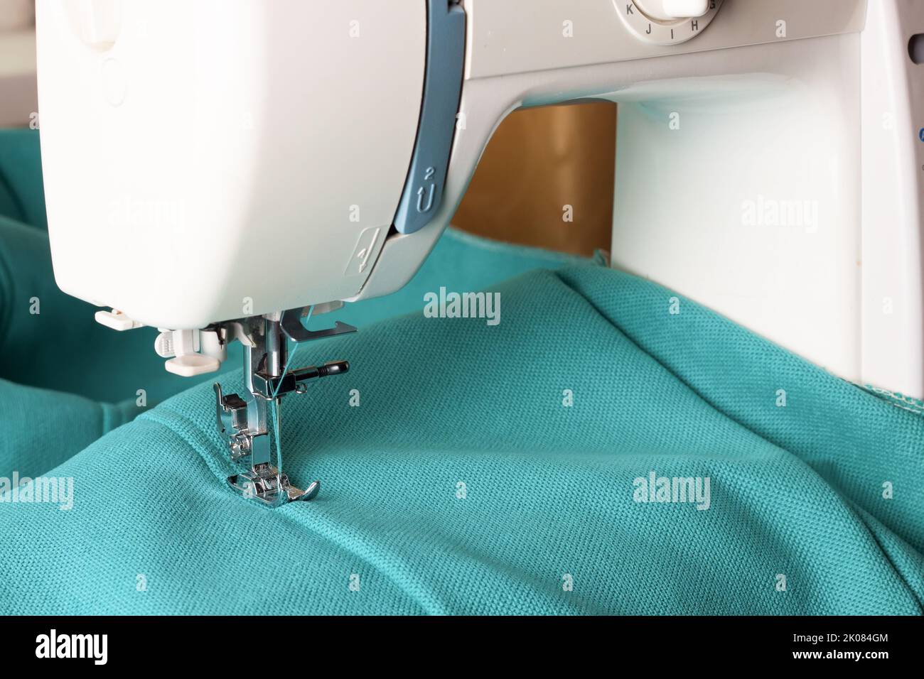 Modern sewing machine working with turquoise fabric. Sewing process ...