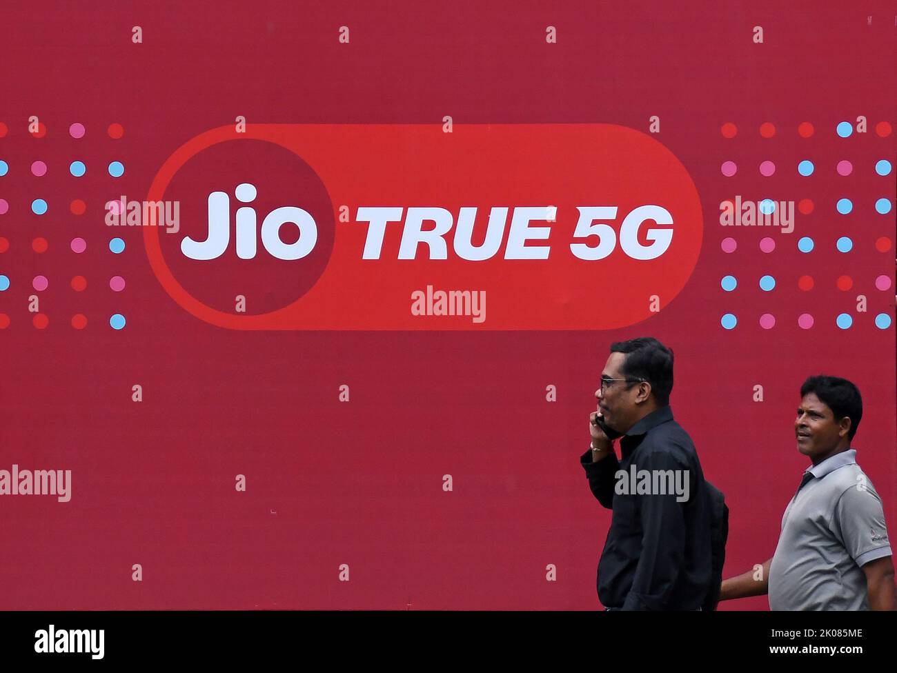 A man talking on phone walks past Jio 5G branding in Mumbai. Reliance ...