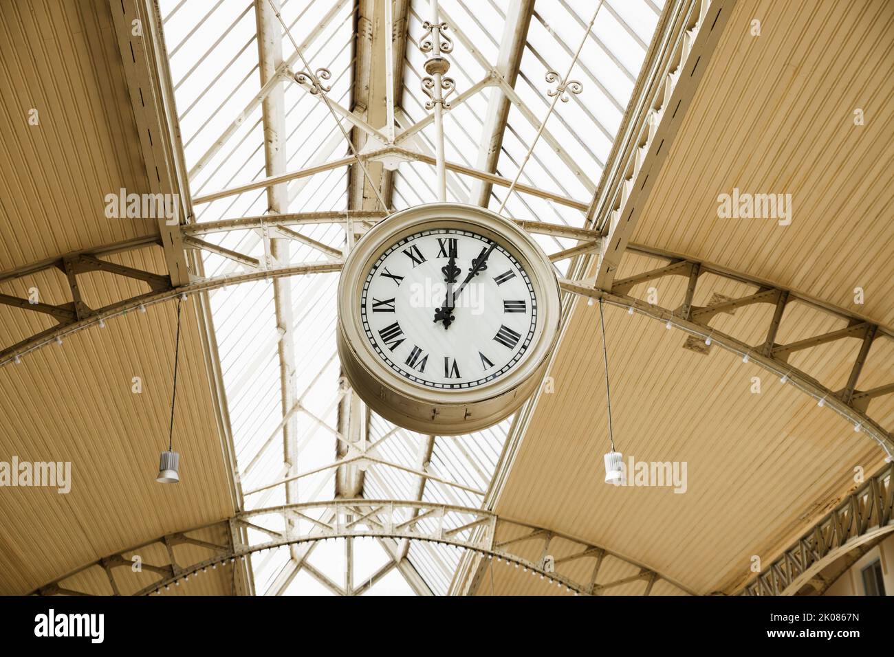 Round Roman clock at railway or subway station. Twelve o'clock, five ...