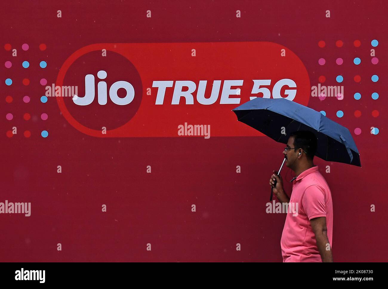 Mumbai, India. 10th Sep, 2022. A man holding an umbrella walks past Jio ...