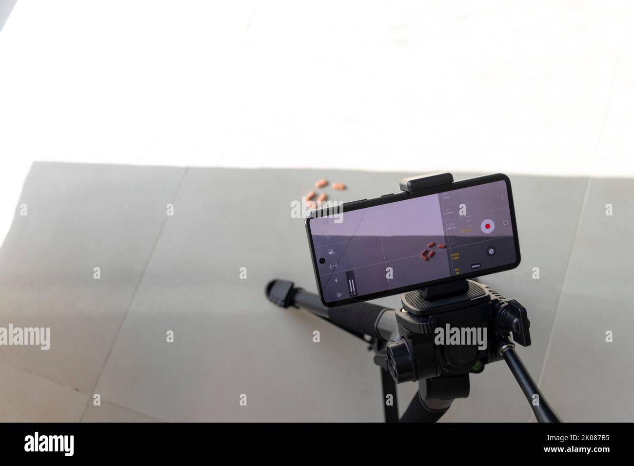 Close up shot of a phone on tripod capturing medicine on the surface ...