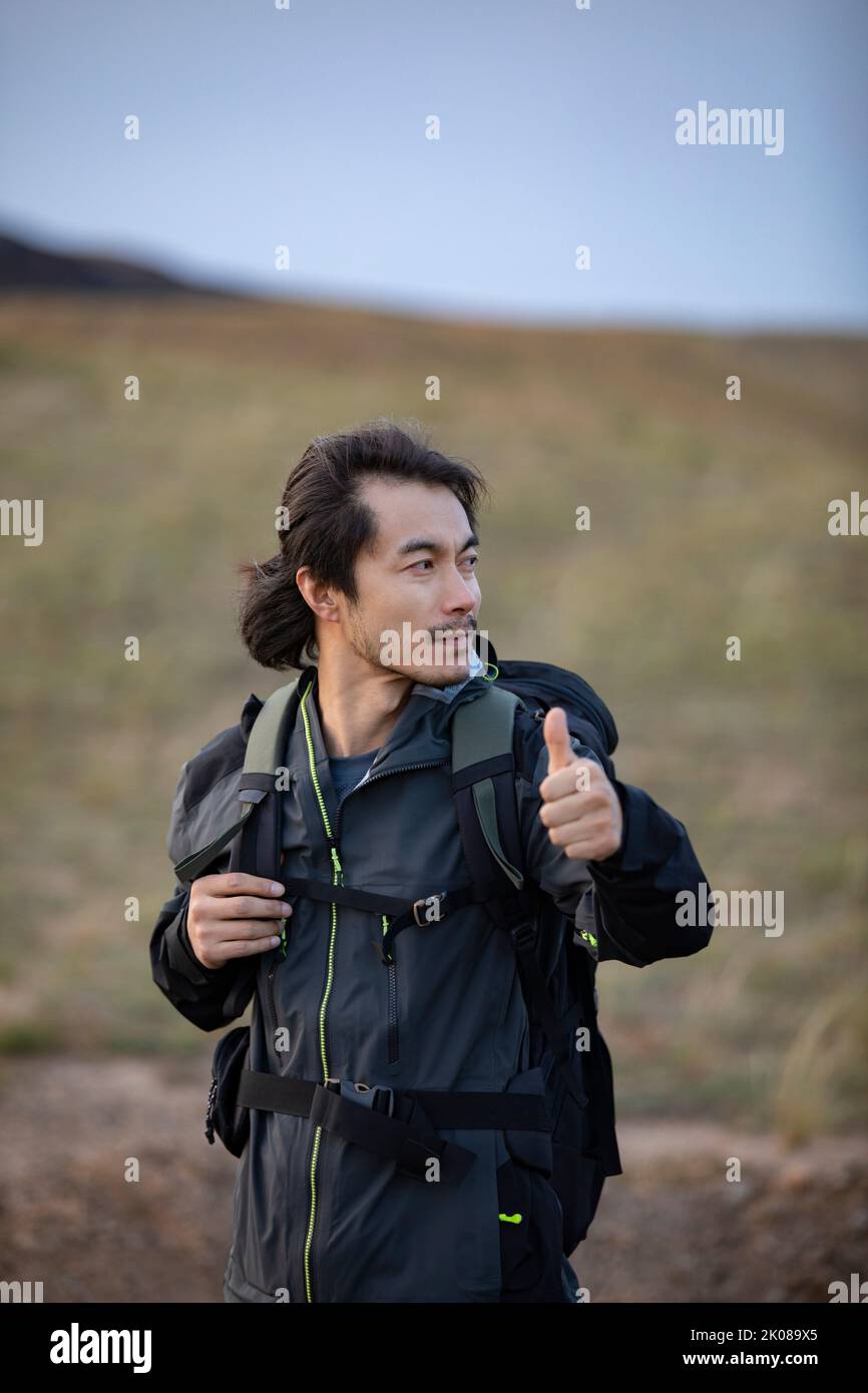 Chinese mid adult man hitchhiking on the road Stock Photo - Alamy