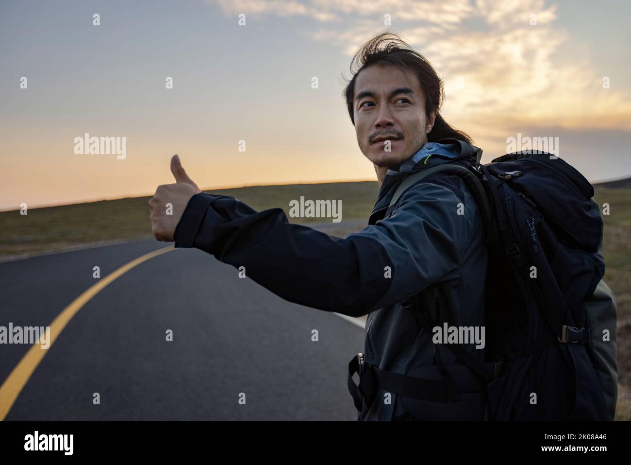 Chinese mid adult man hitchhiking on the road Stock Photo - Alamy