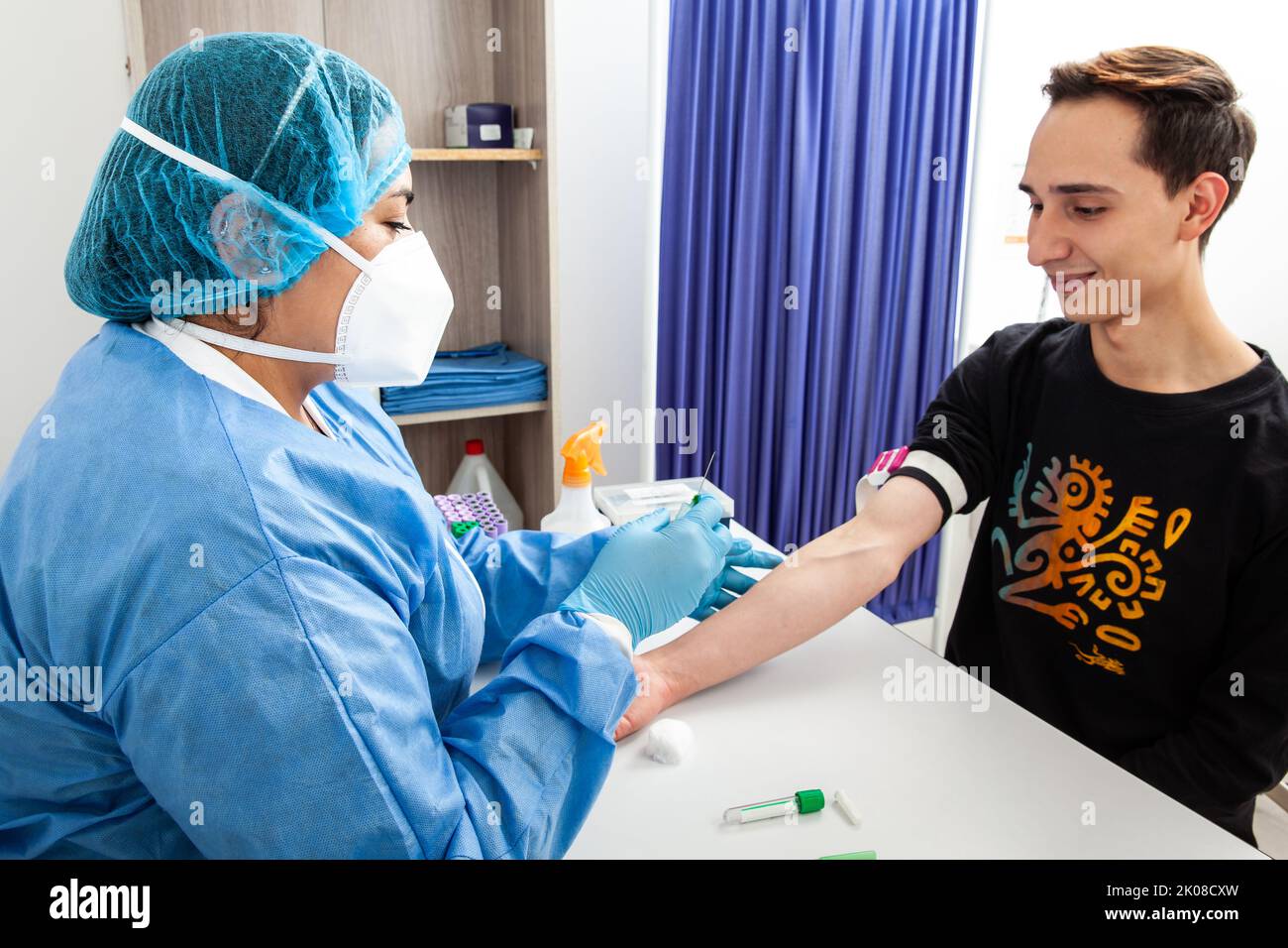 Young Female nurse collecting a blood sample from a male patient in a ...