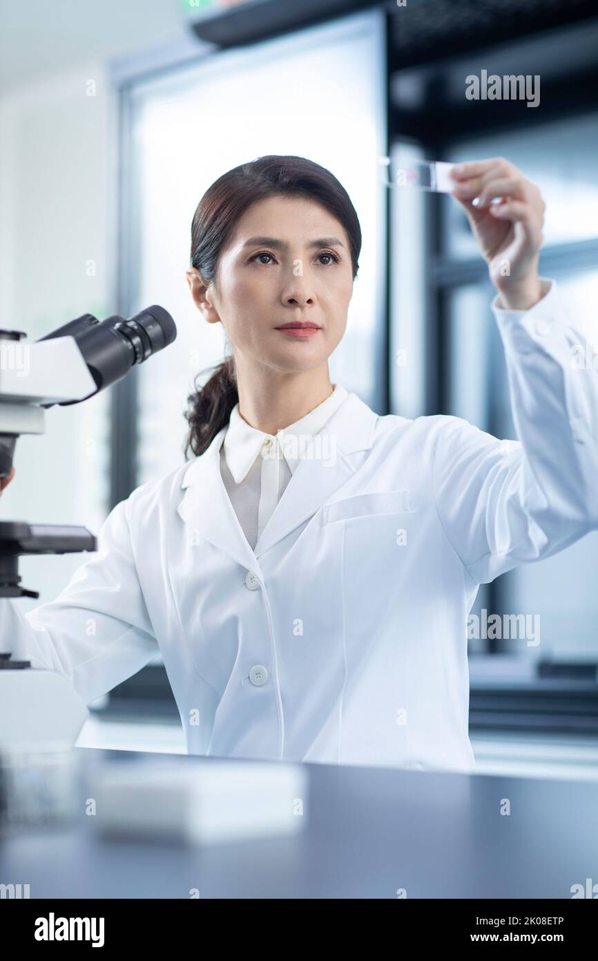 Chinese scientist looking at a microscope slide Stock Photo - Alamy