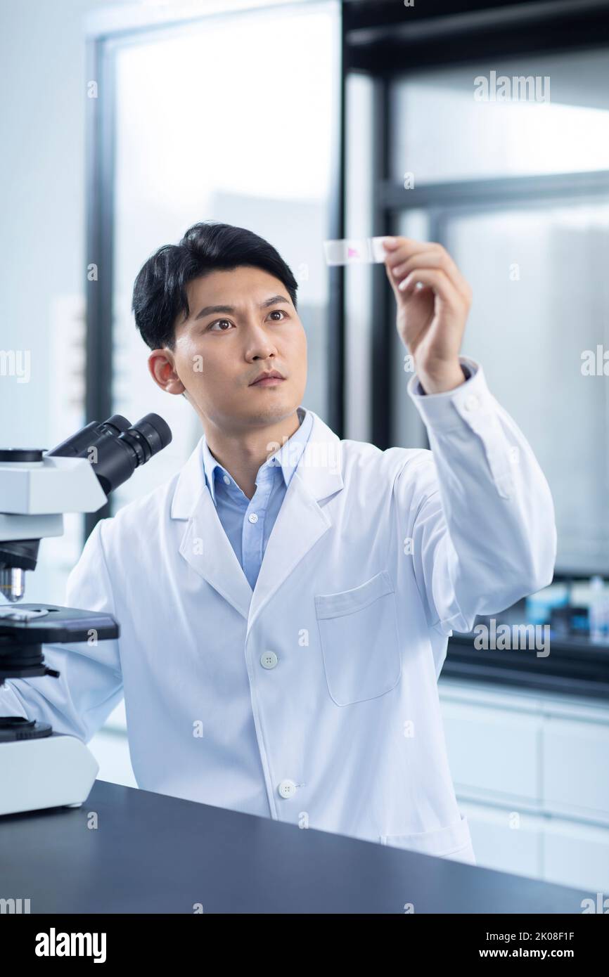 Chinese scientist looking at a microscope slide Stock Photo - Alamy
