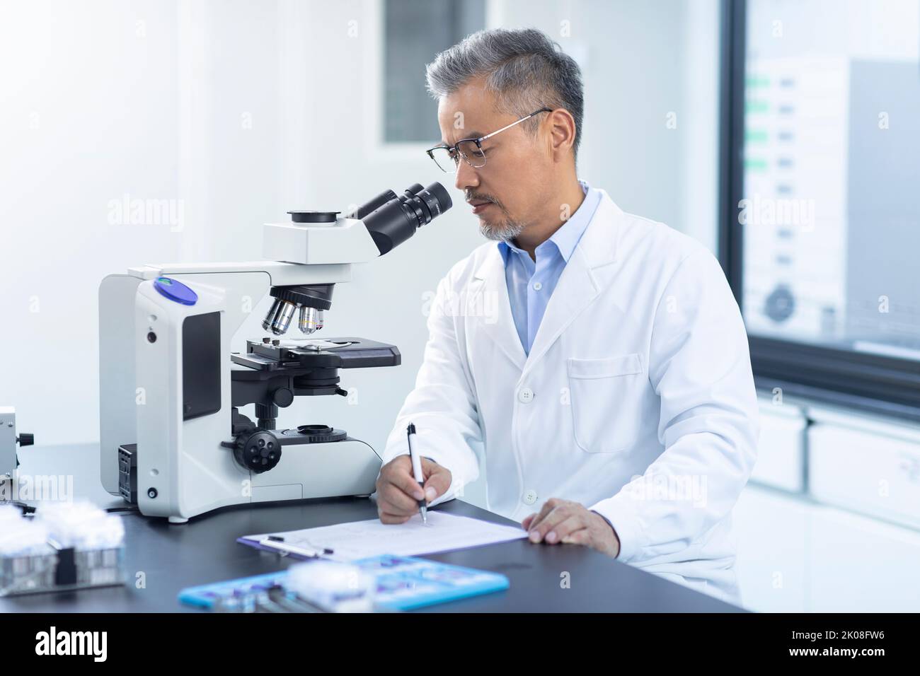 Chinese scientist looking through a microscope Stock Photo - Alamy