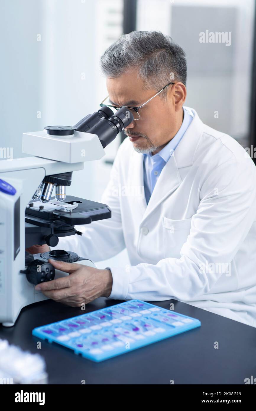 Chinese scientist looking through a microscope Stock Photo - Alamy