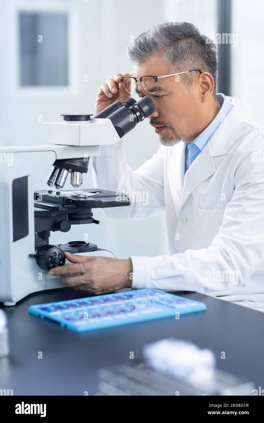 Chinese scientist looking through a microscope Stock Photo - Alamy