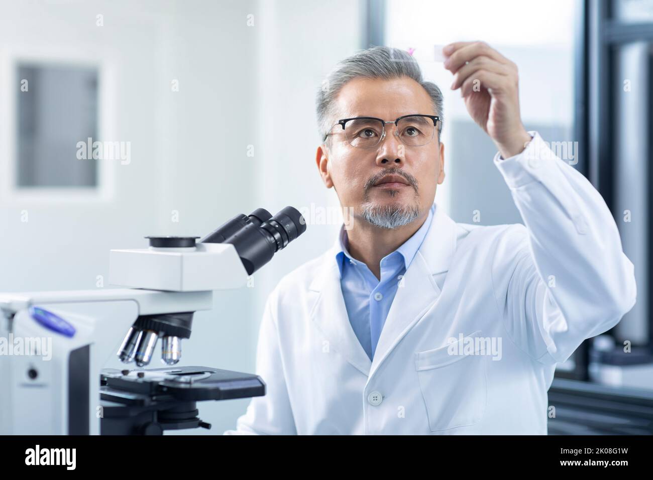 Chinese scientist looking at a microscope slide Stock Photo - Alamy