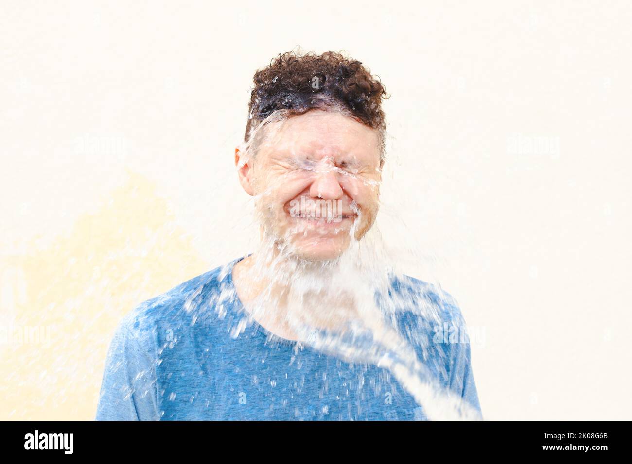 Wet smiling young caucasian man in blue t-shirt with closed eyes in ...