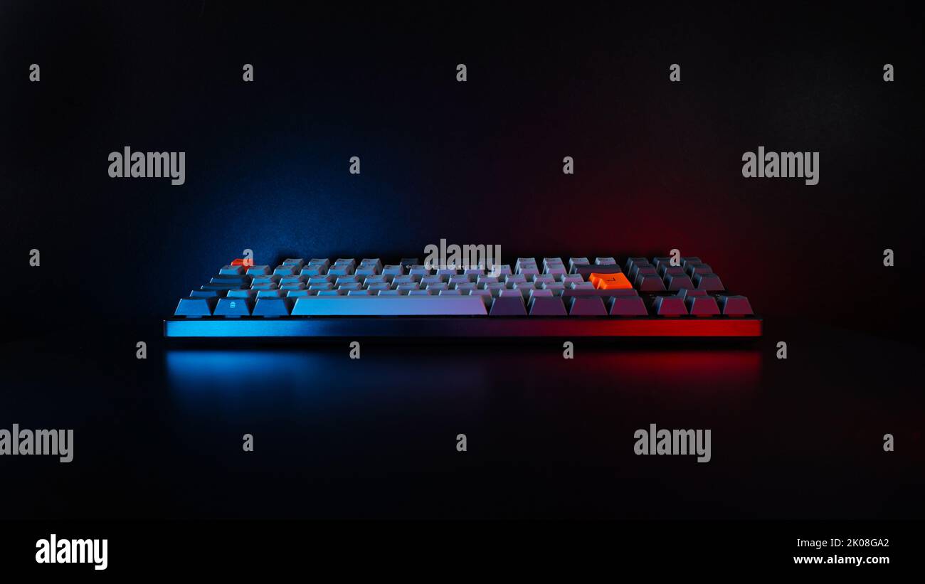 Gaming keyboard with orange accent key caps illuminated with red and ...