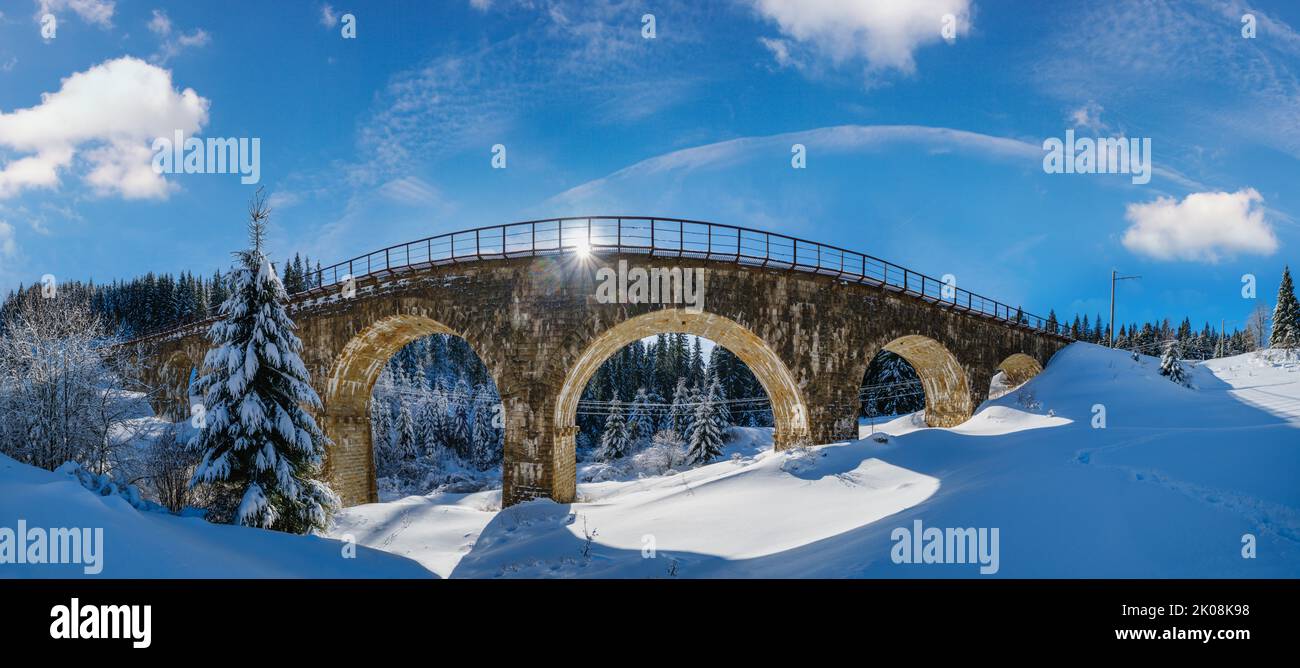 Stone viaduct (arch bridge) on railway through mountain snowy fir ...