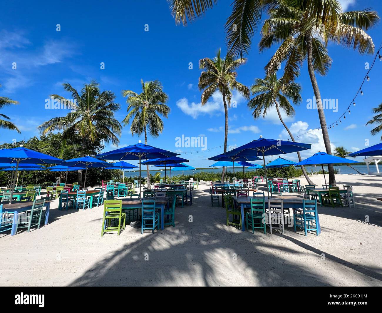 A typical beach restaurant with colorful tables, chairs and umbrellas ...
