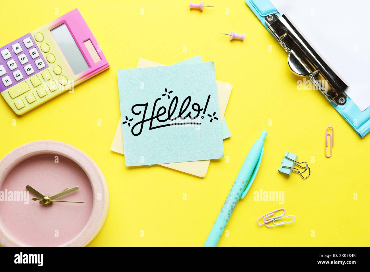 Sticky note with word HELLO, calculator, clock and stationery on yellow ...