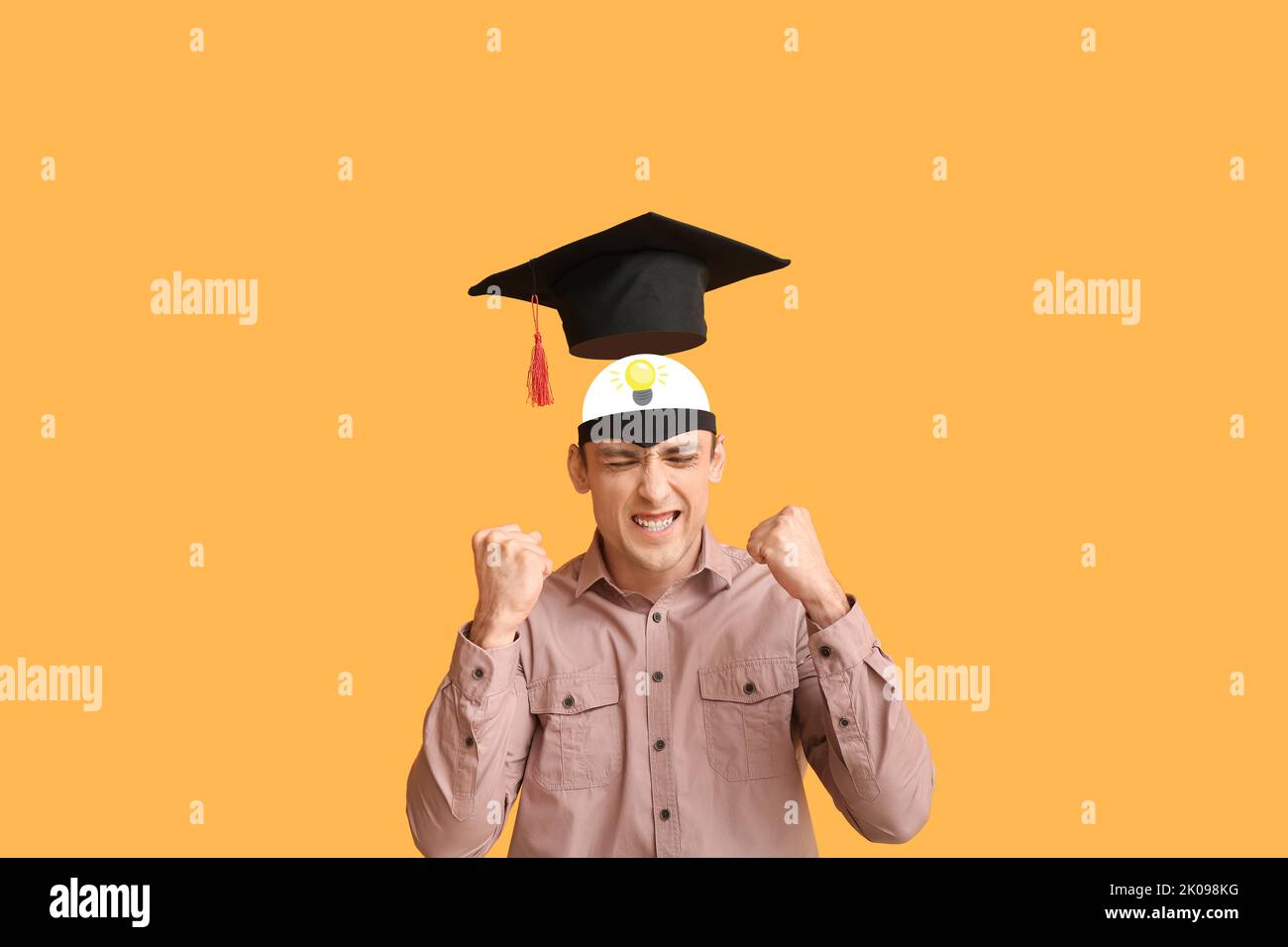 Smart man with graduation hat on orange background Stock Photo - Alamy