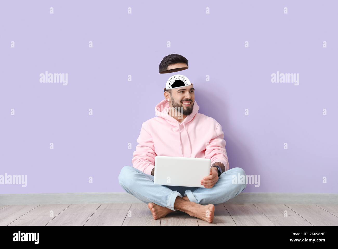 Smart man with laptop sitting near lilac wall Stock Photo - Alamy