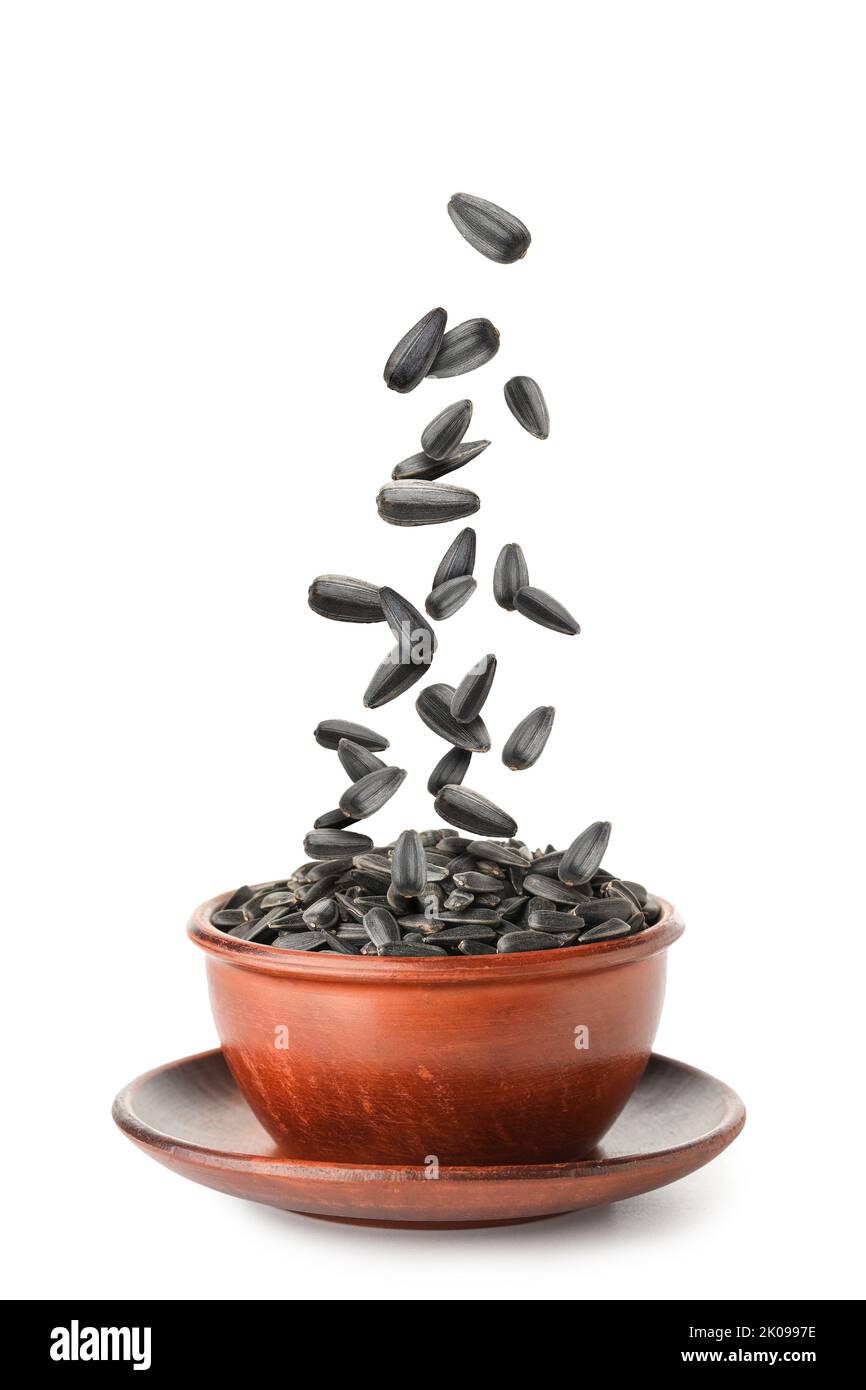 Sunflower seeds falling into bowl on white background Stock Photo - Alamy