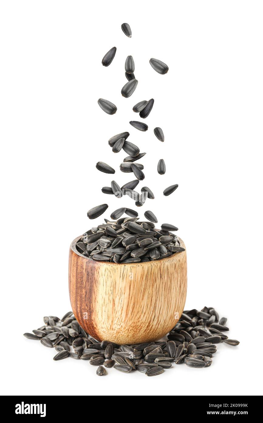 Sunflower seeds falling into wooden bowl on white background Stock ...