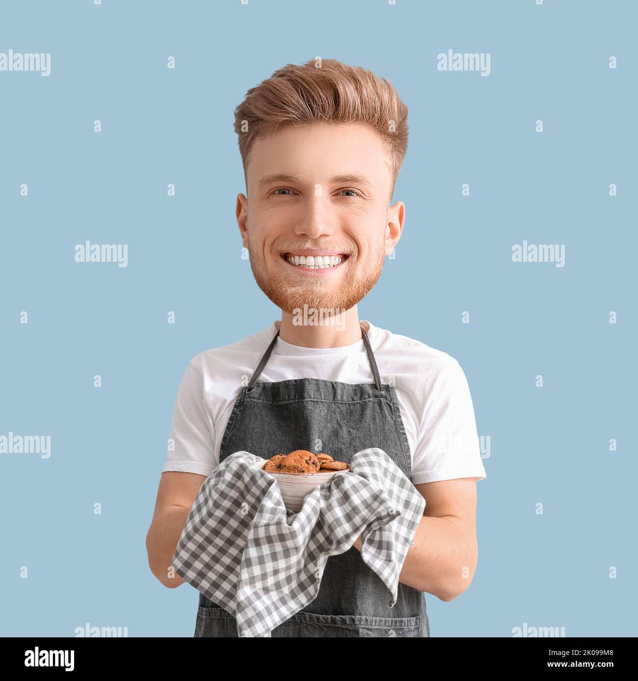 Funny male baker with big head holding cookies on light blue background ...