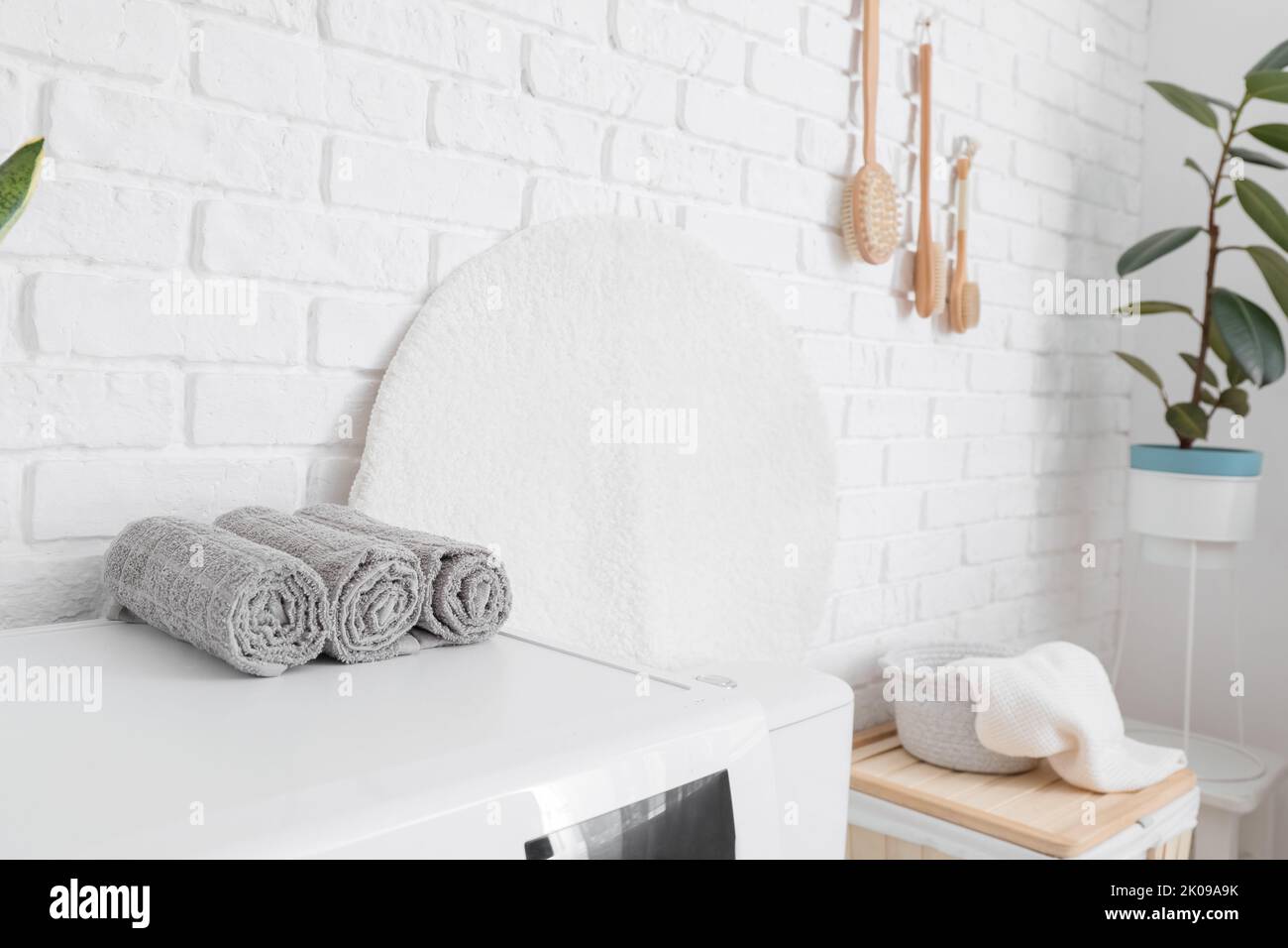 Rolls of towels on washing machine near white brick wall in bathroom ...