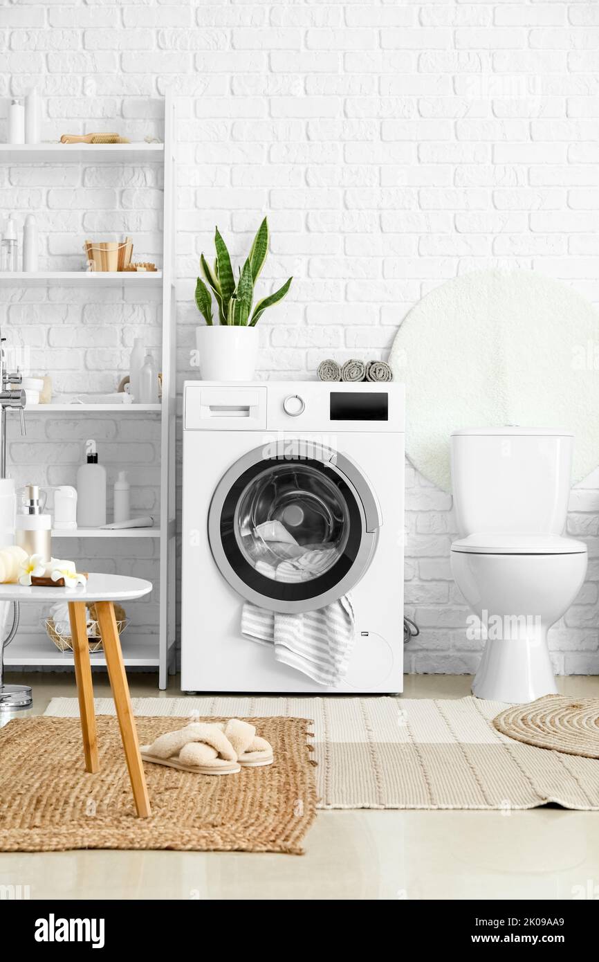 Interior of bathroom with modern washing machine, toilet bowl and shelf ...