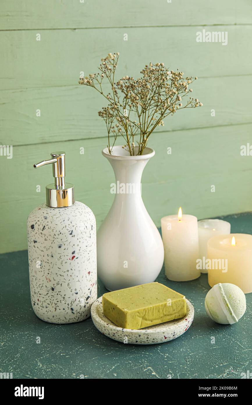 Set of bath supplies with burning candles and flowers on color table ...
