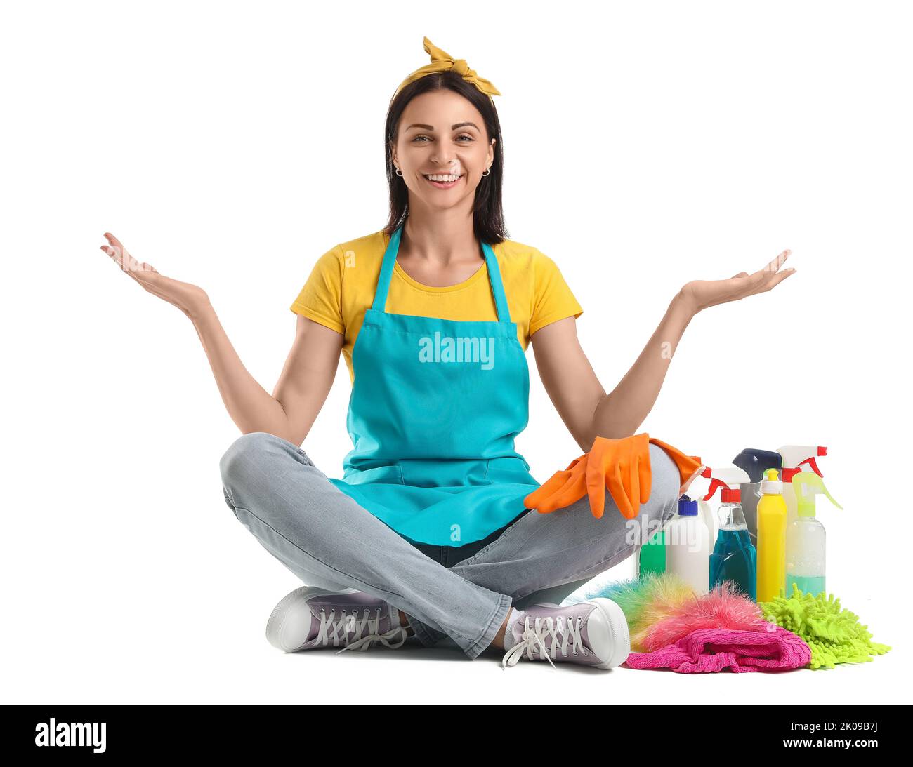 Beautiful woman with cleaning supplies sitting on white background ...