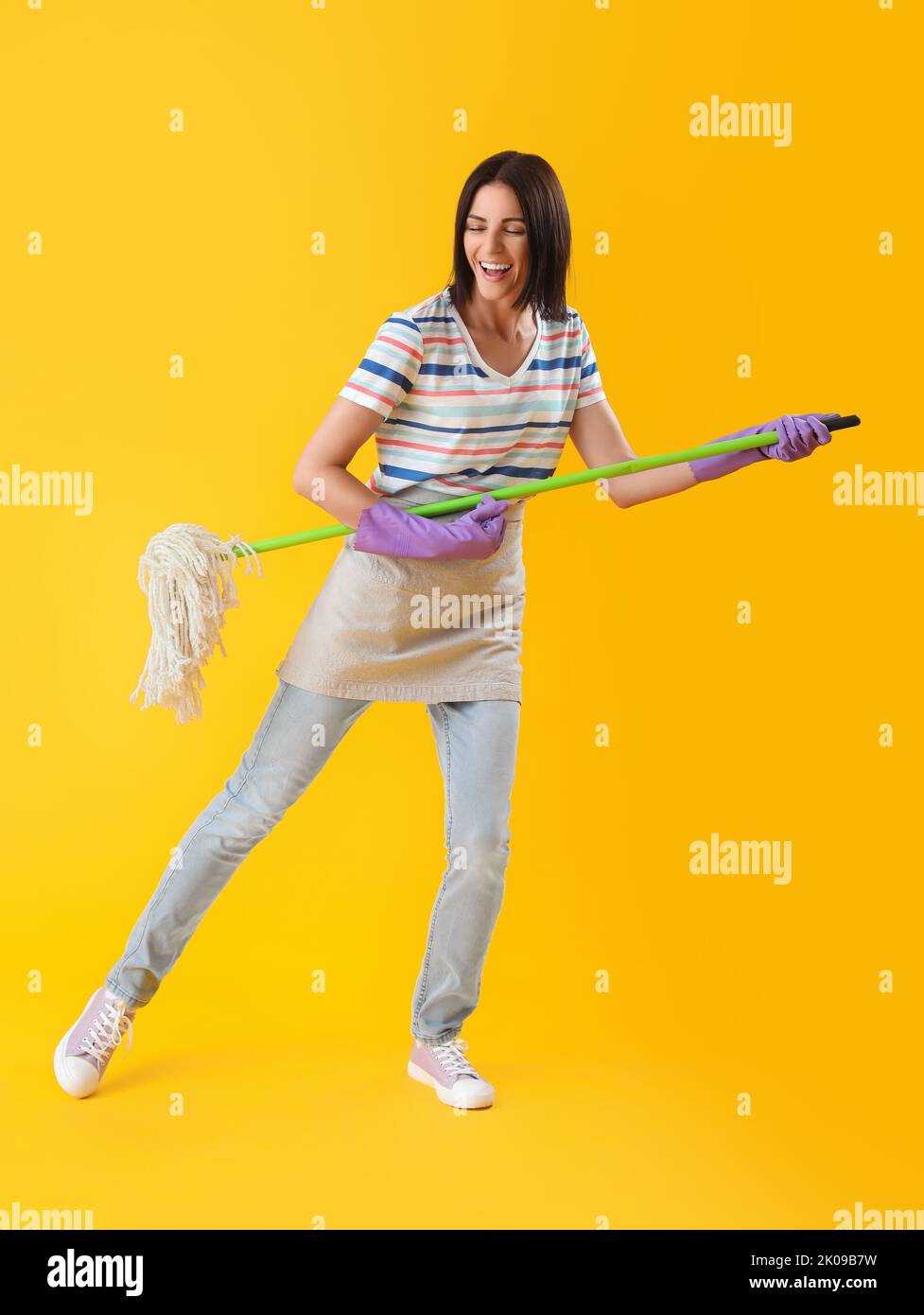 Beautiful woman with mop on yellow background Stock Photo - Alamy