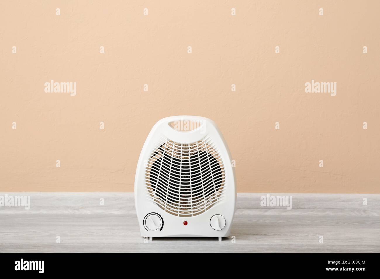 Electric fan heater near beige wall Stock Photo - Alamy