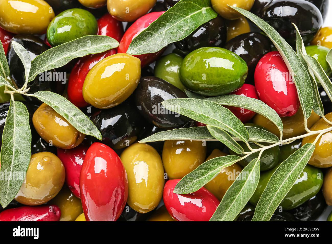 Different kinds of tasty olives and leaves as background, closeup Stock ...