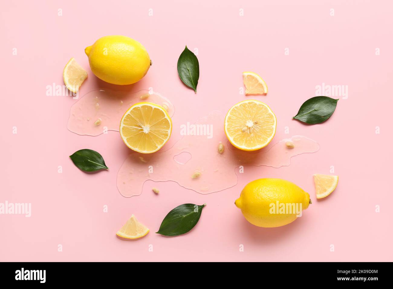 Composition with cut lemons, spilled juice and leaves on pink ...