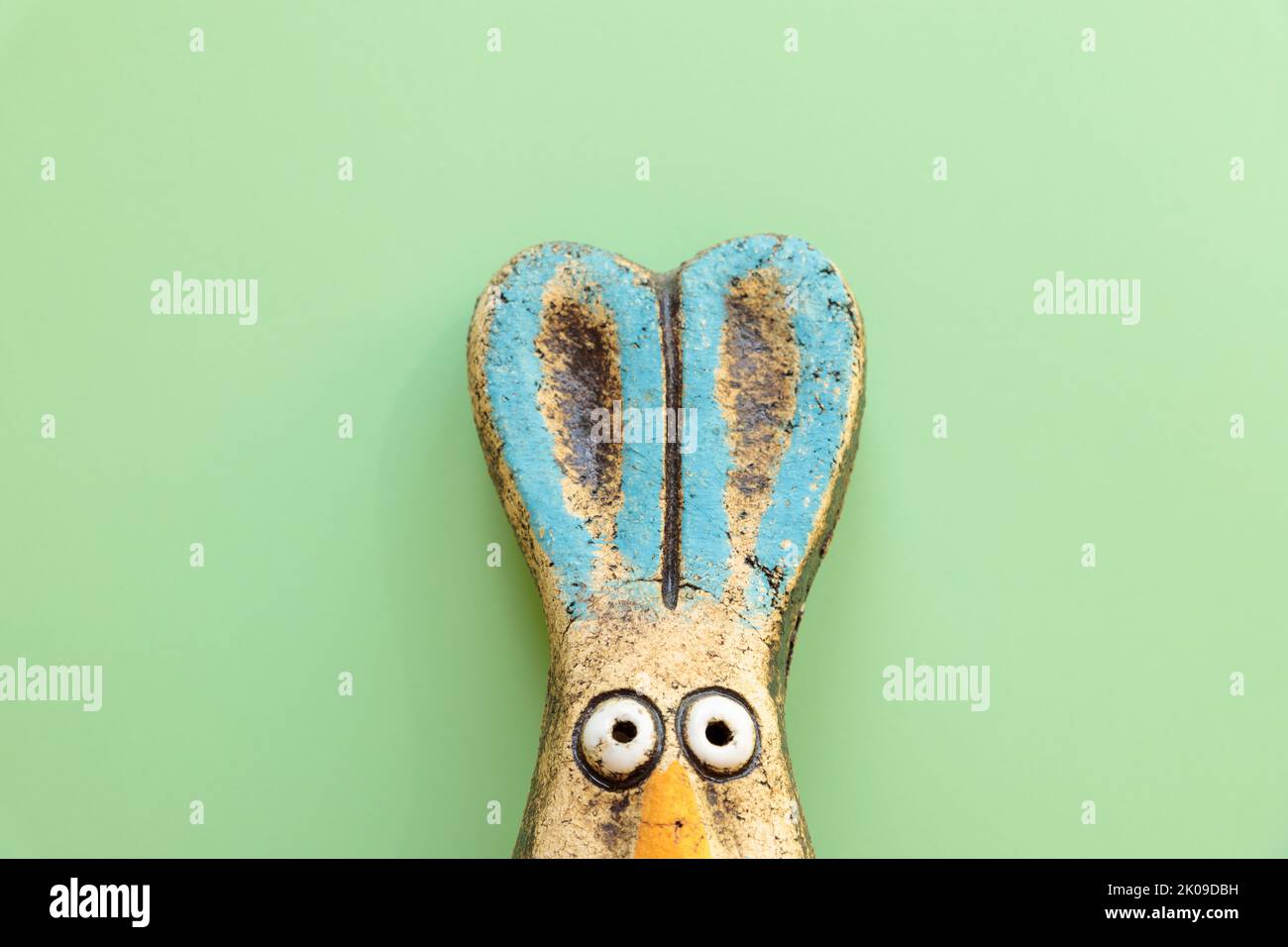 Shocked eyes and ears of toy hare on green background with copy space ...