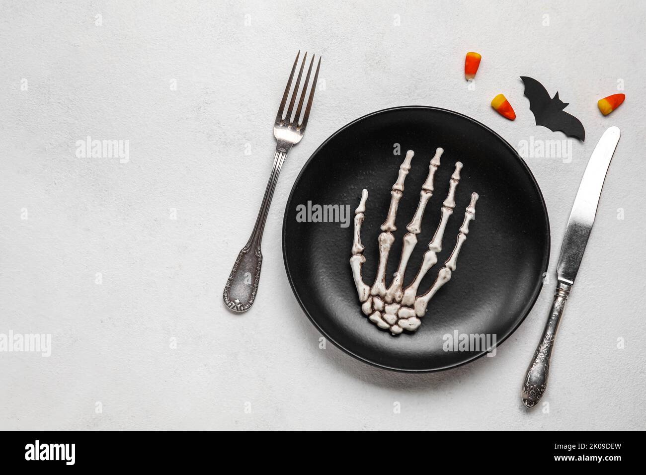 Table setting with skeleton hand in plate and Halloween decor on light ...