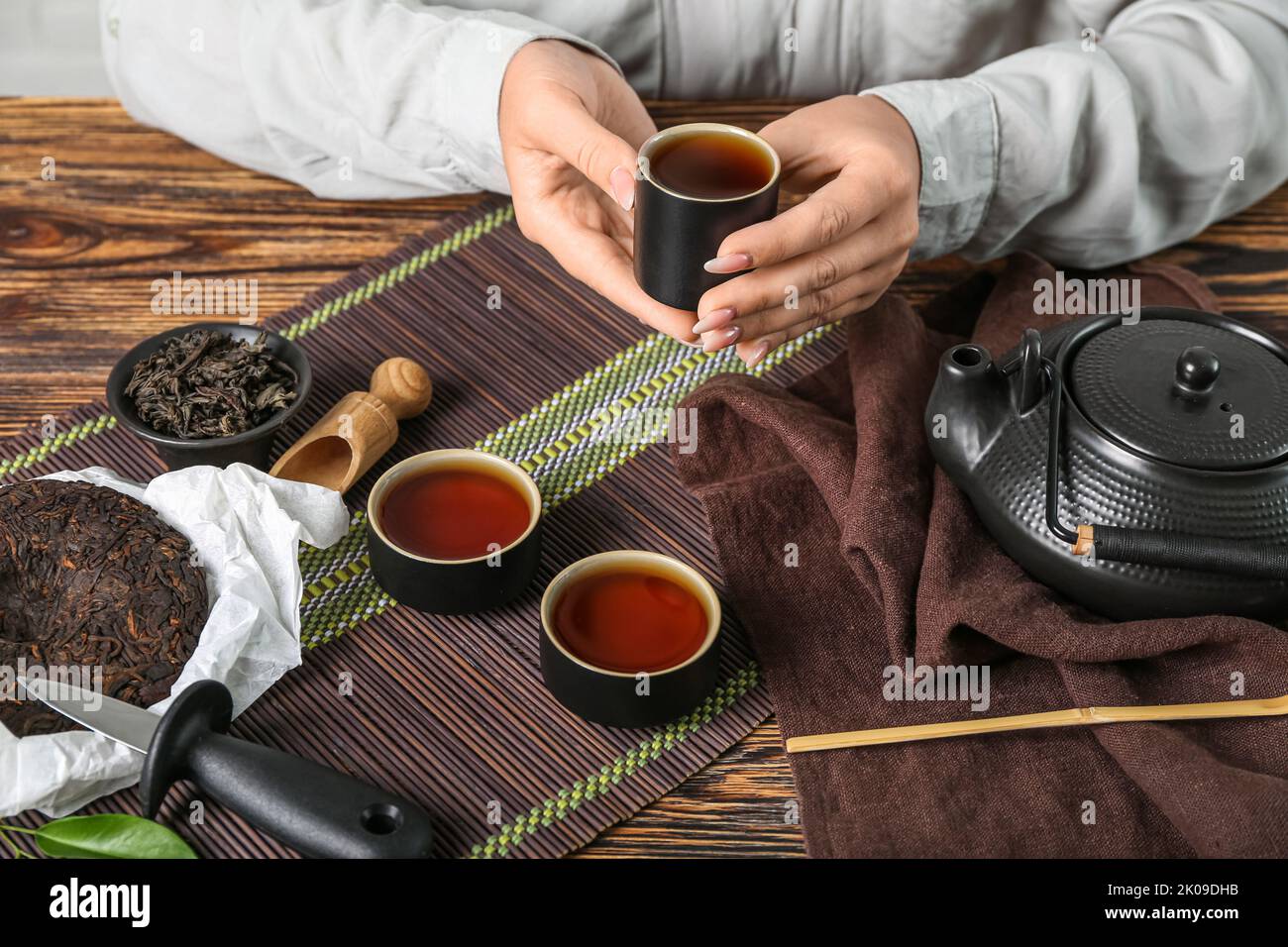 Woman with cup of puer tea at wooden table, closeup Stock Photo - Alamy