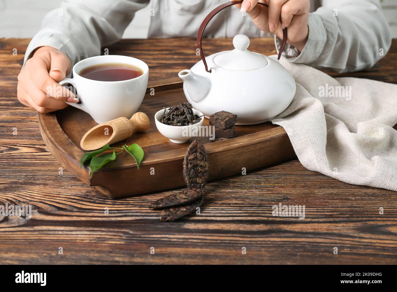 Woman with pot and cup of puer tea at wooden table, closeup Stock Photo ...