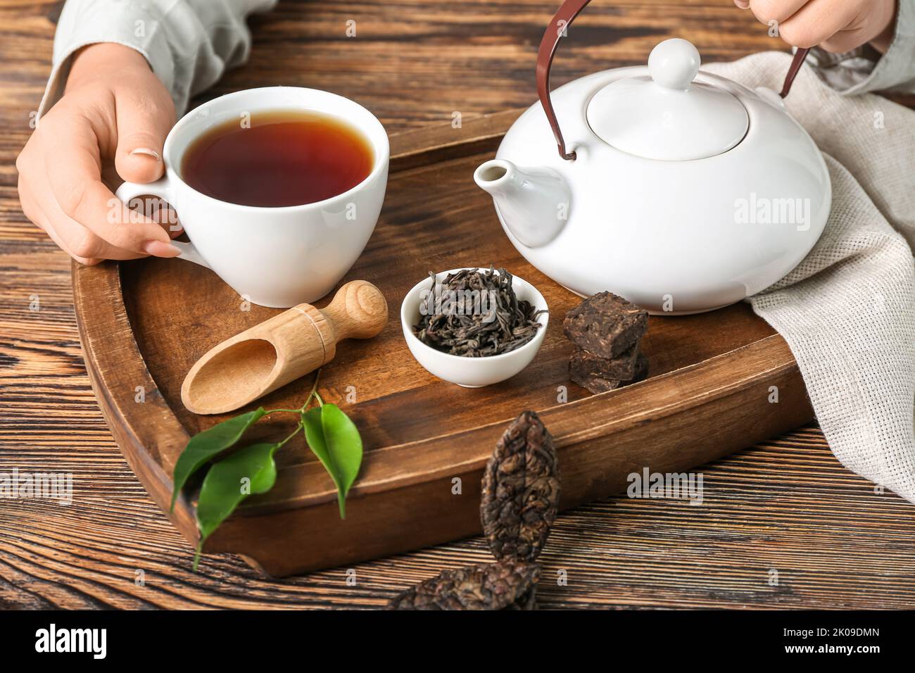 Woman with pot and cup of puer tea at wooden table, closeup Stock Photo ...