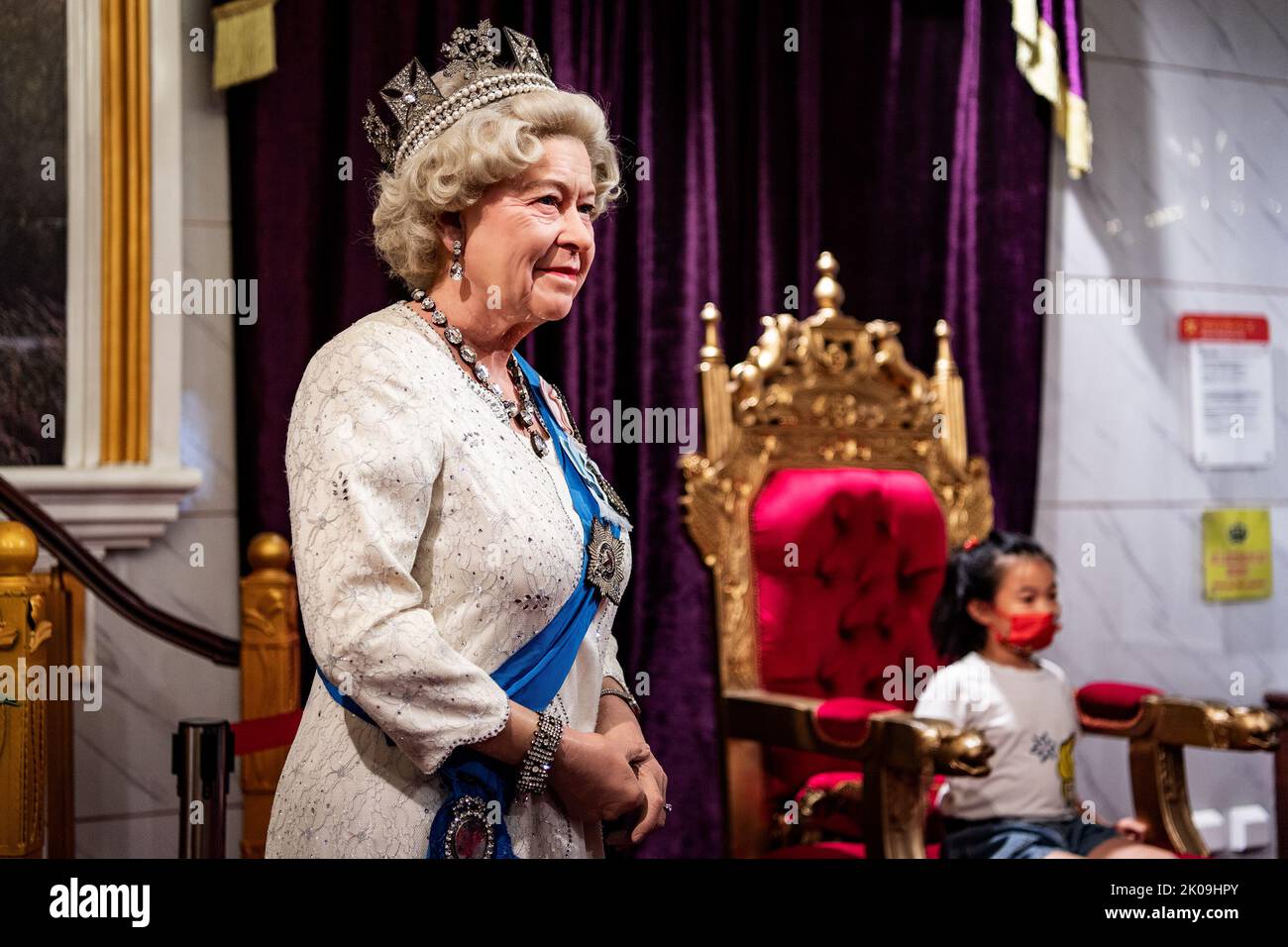A kid poses next to a wax sculpture of Queen Elizabeth II at Wuhan ...