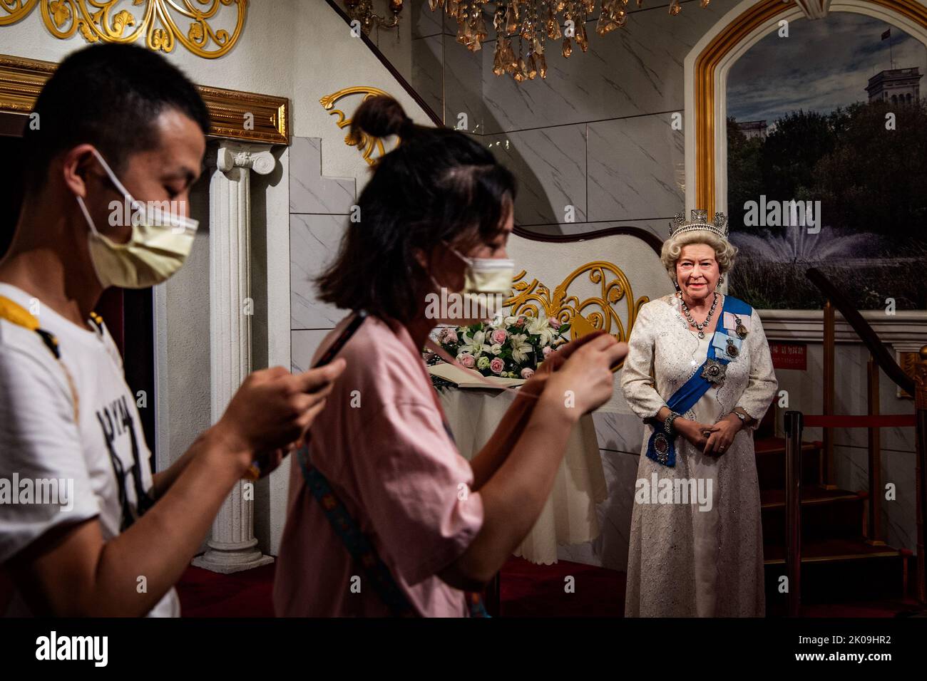 Tourists take photo in front of a wax figure of Britain's Queen ...