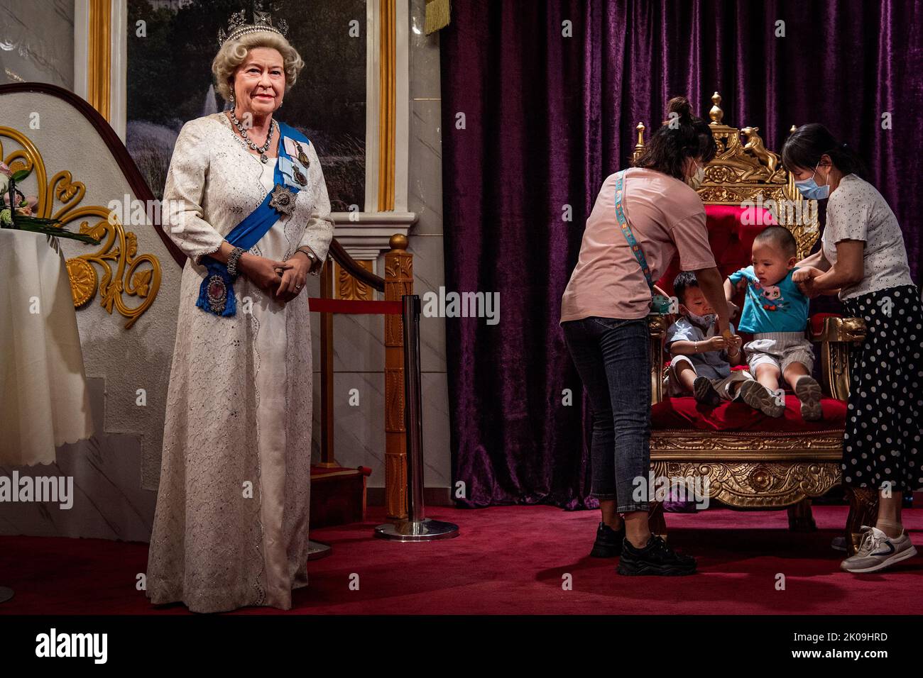 Tourists pose next to a wax figure of Britain's Queen Elizabeth II at ...