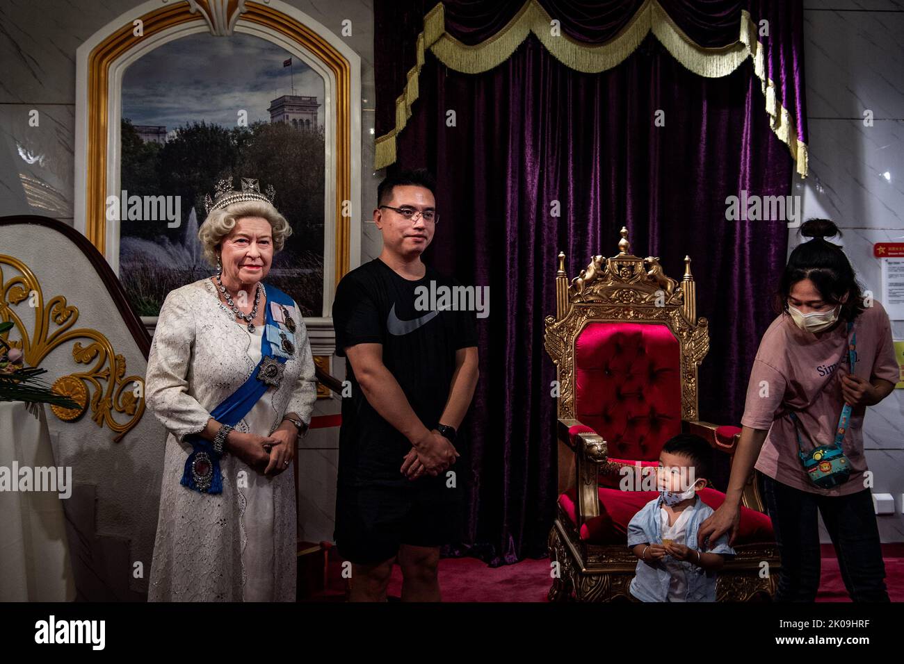 A man poses next to wax sculpture of Queen Elizabeth II at Wuhan Madame ...