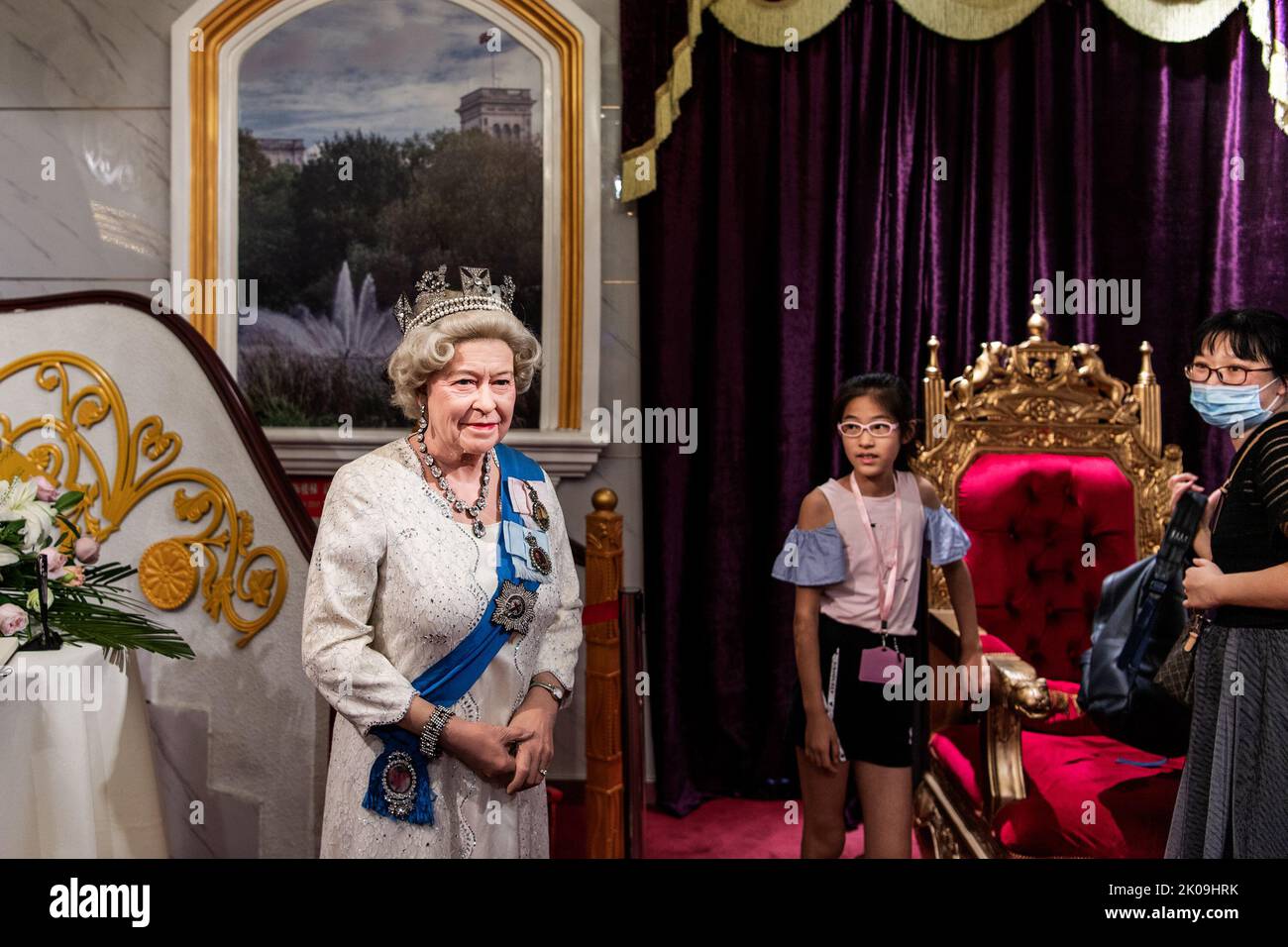 Tourists stand beside a wax figure of Britain's Queen Elizabeth II at ...